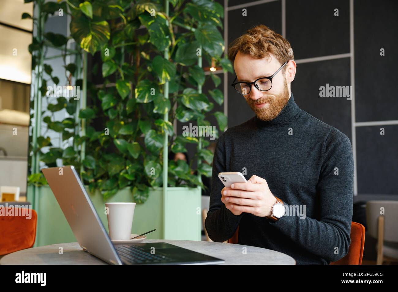 A young red-haired guy, a programmer or businessman in glasses, sits in ...
