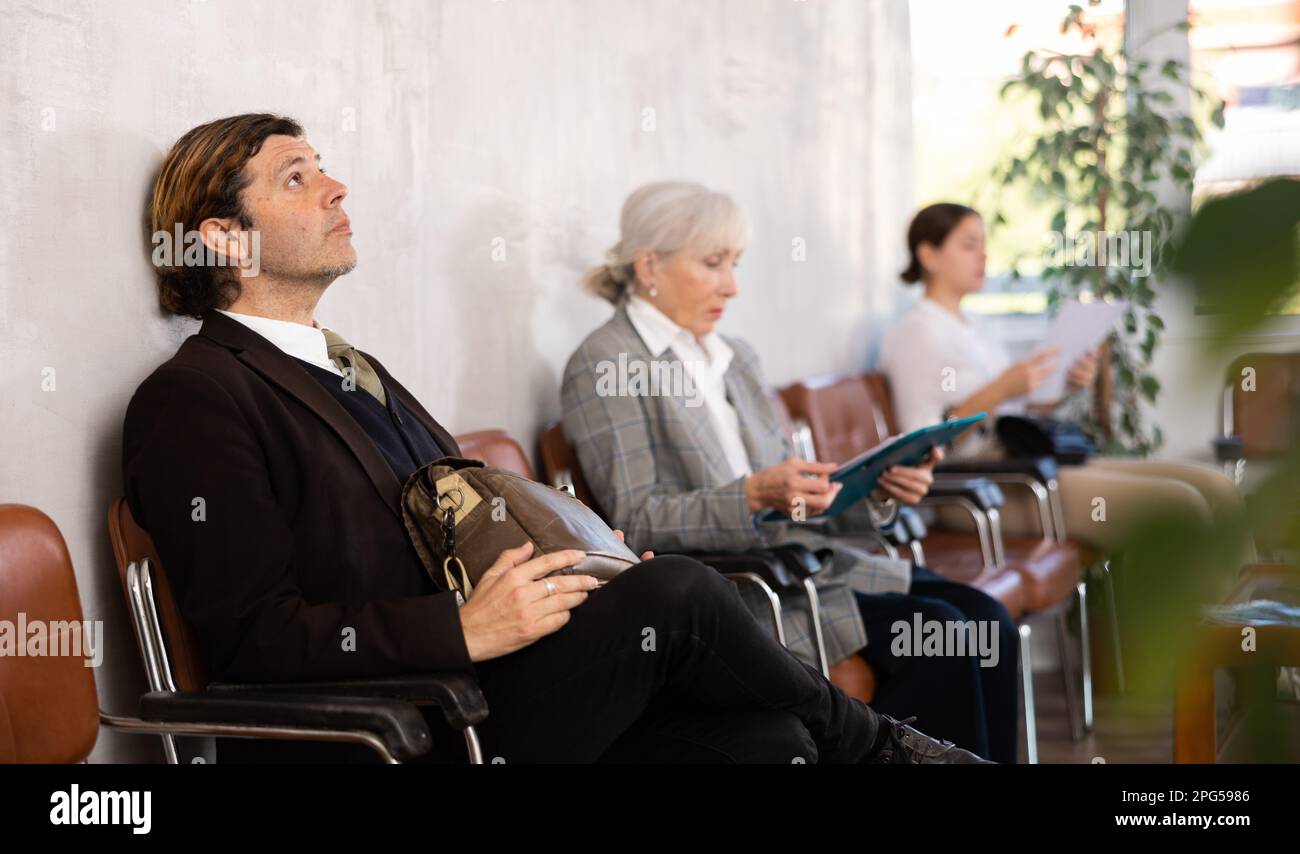 Serious-minded male candidate siting on chair and waiting for job ...