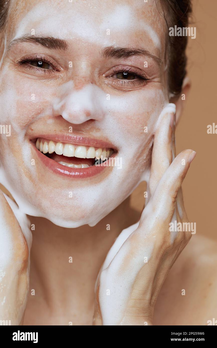 smiling modern female with foaming facial cleanser washing face ...