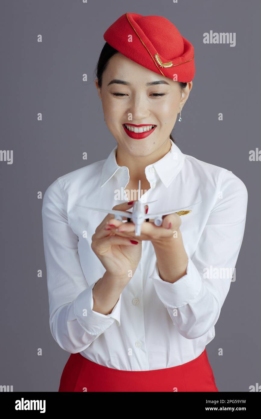 smiling elegant asian female flight attendant in red skirt and hat ...