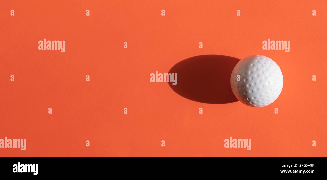 White dimple hockey ball and golf ball on orange color background ...