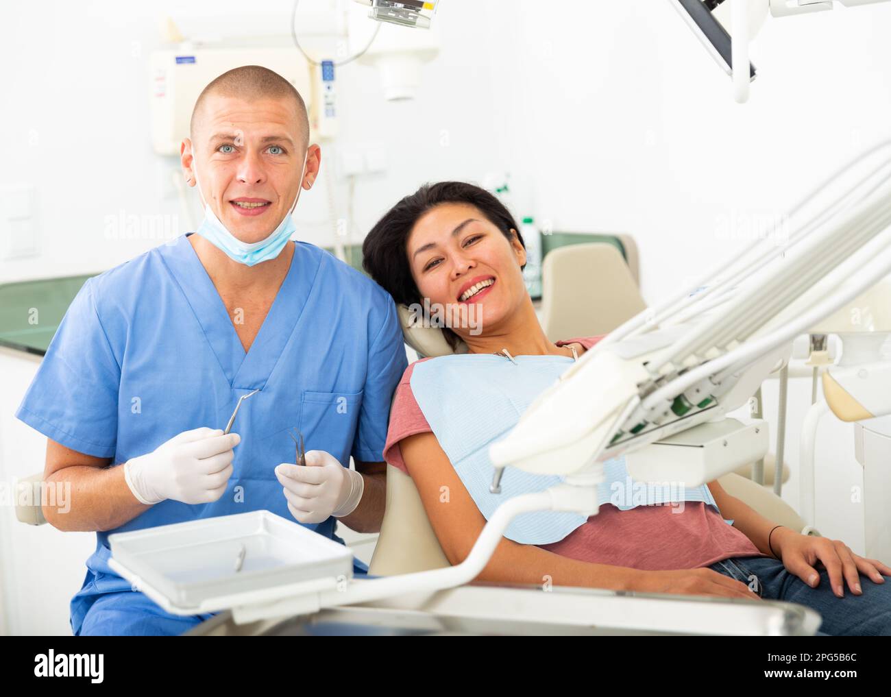 Dentist and happy patient sitting in dental chair Stock Photo - Alamy