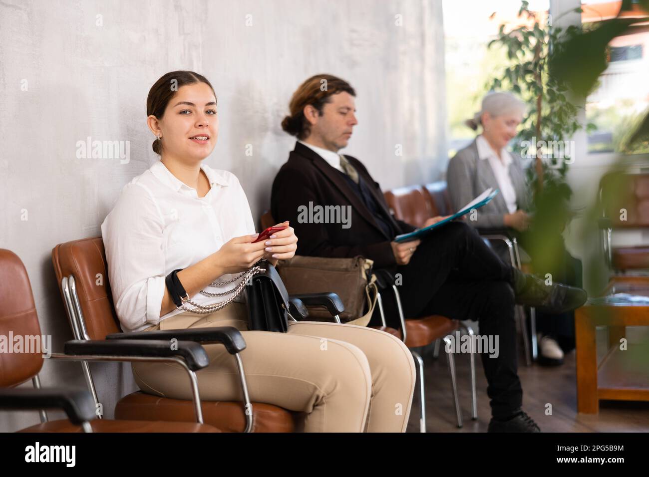 Serious-minded female candidate siting on chair and waiting for job ...