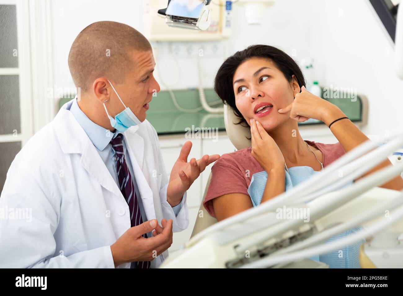 Female patient shows sick tooth to a dentist in dental clinic Stock ...
