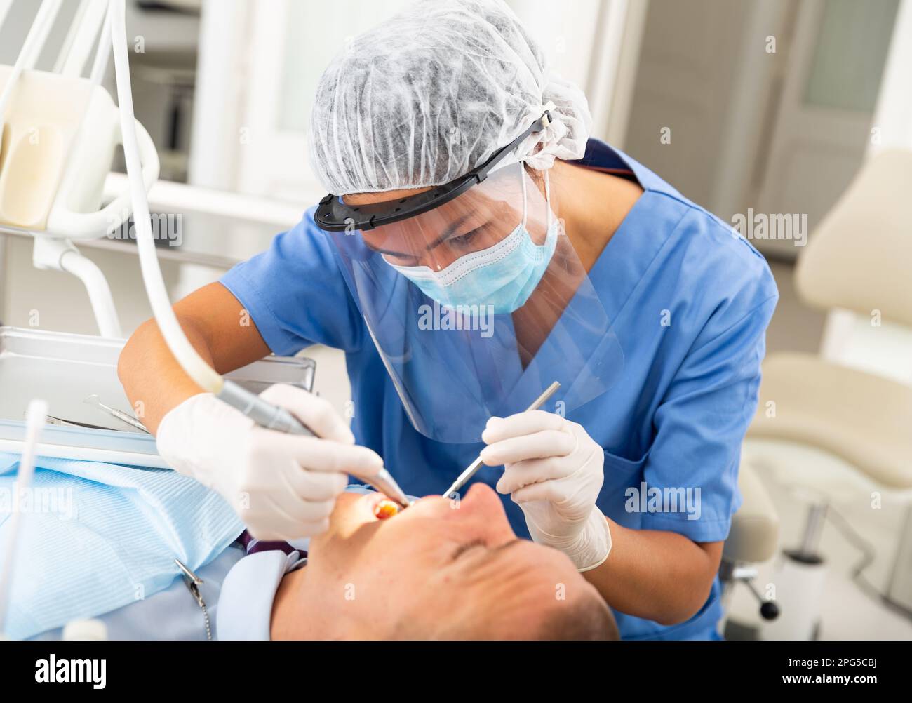 Female dentist drilling tooth to male patient Stock Photo - Alamy