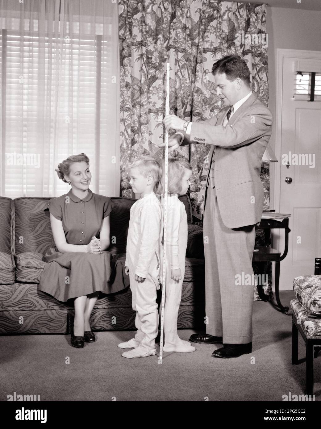 1940s MOTHER AND FATHER IN LIVING ROOM MEASURING HEIGHTS OF SON AND ...