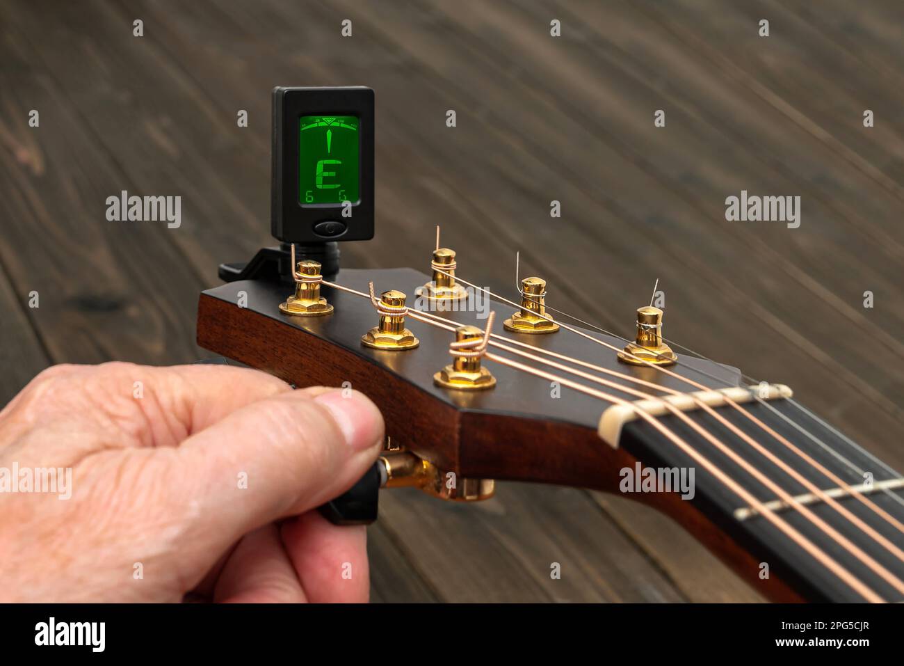 Hand tuning a guitar with a tuner. Close up Stock Photo - Alamy