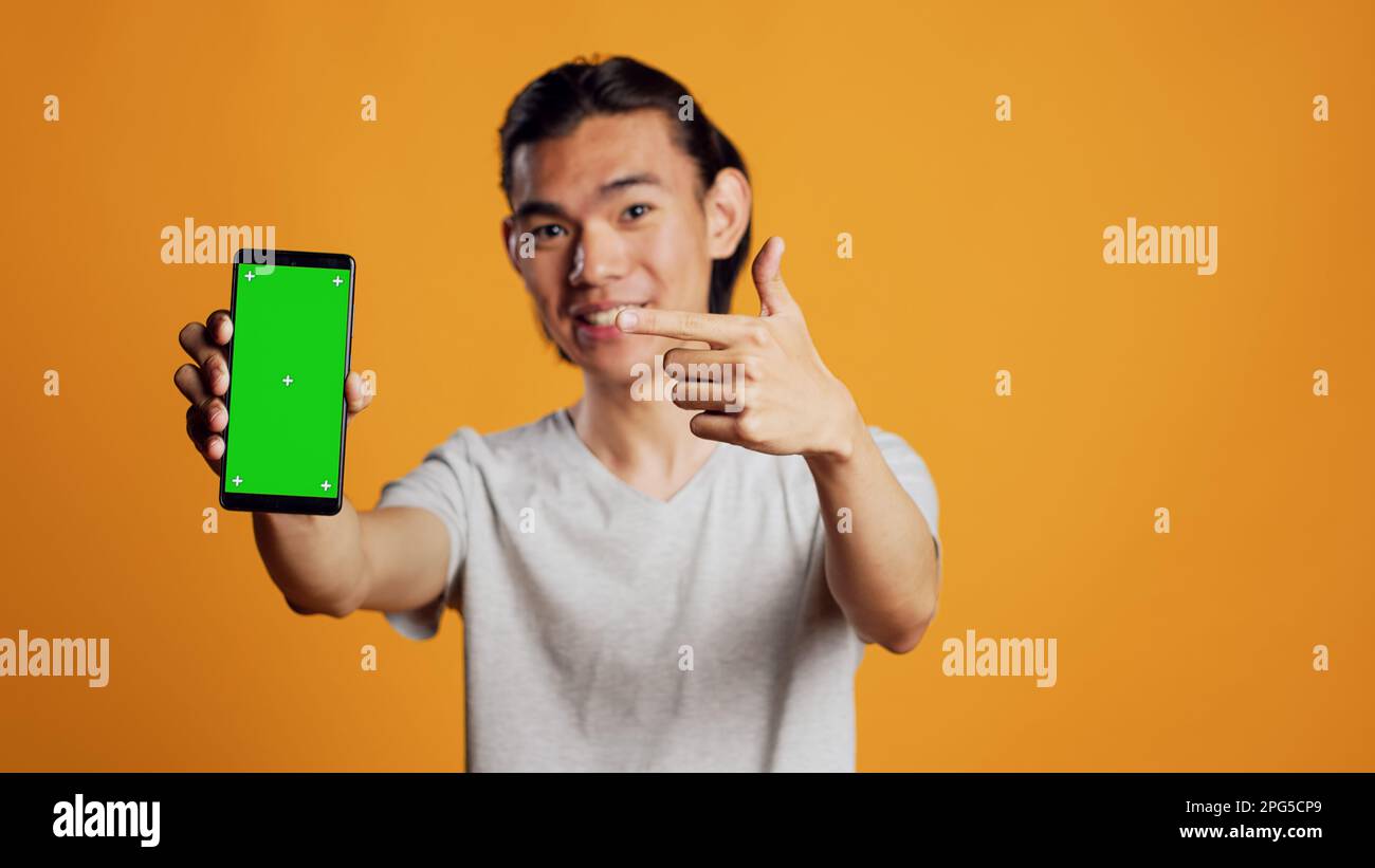 Positive man using greenscreen display on mobile phone, showing ...
