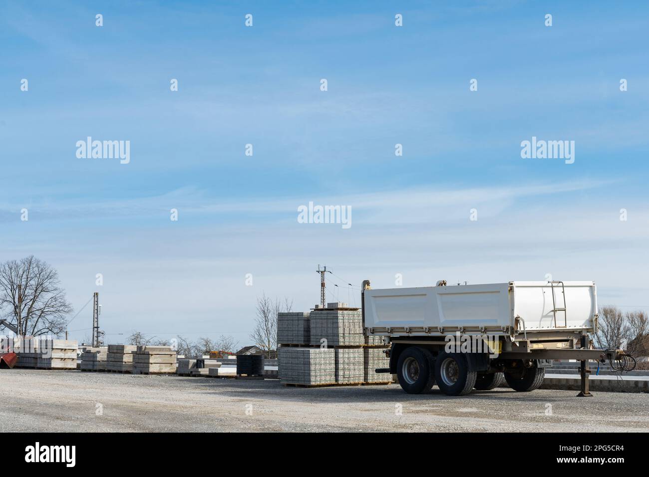 Construction site with empty car trailer and building materials stacked ...