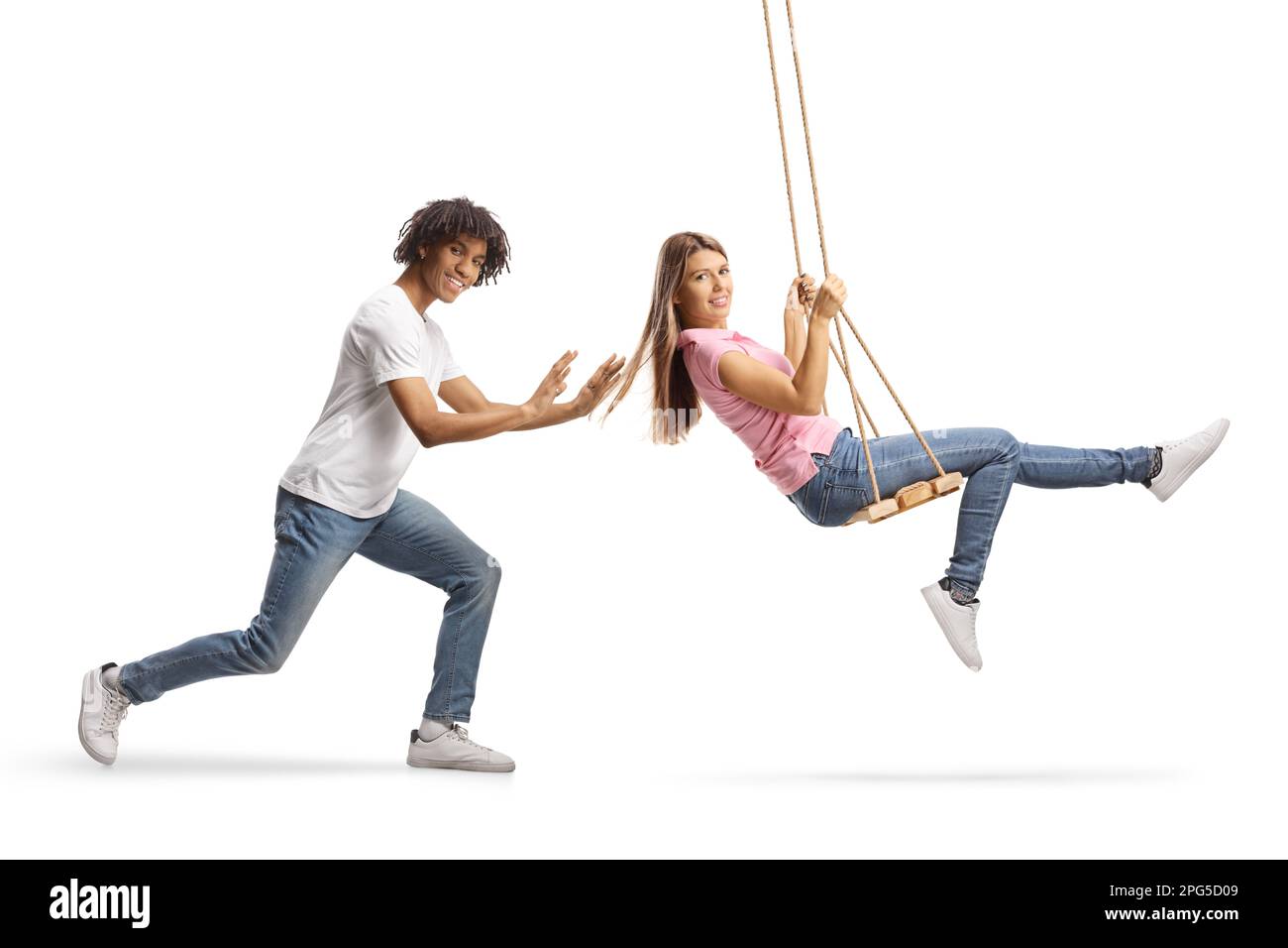 Young african american guy pushing a caucasian female on a swing ...
