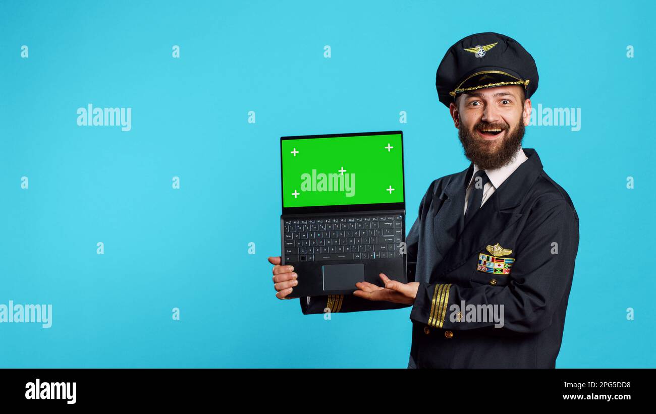 Happy young pilot holding laptop with greenscreen, using chroma key ...
