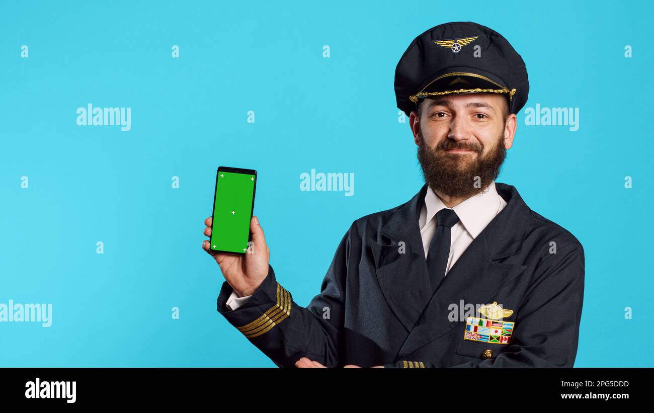 Young aviator using greenscreen dressed as captain, showing smartphone ...