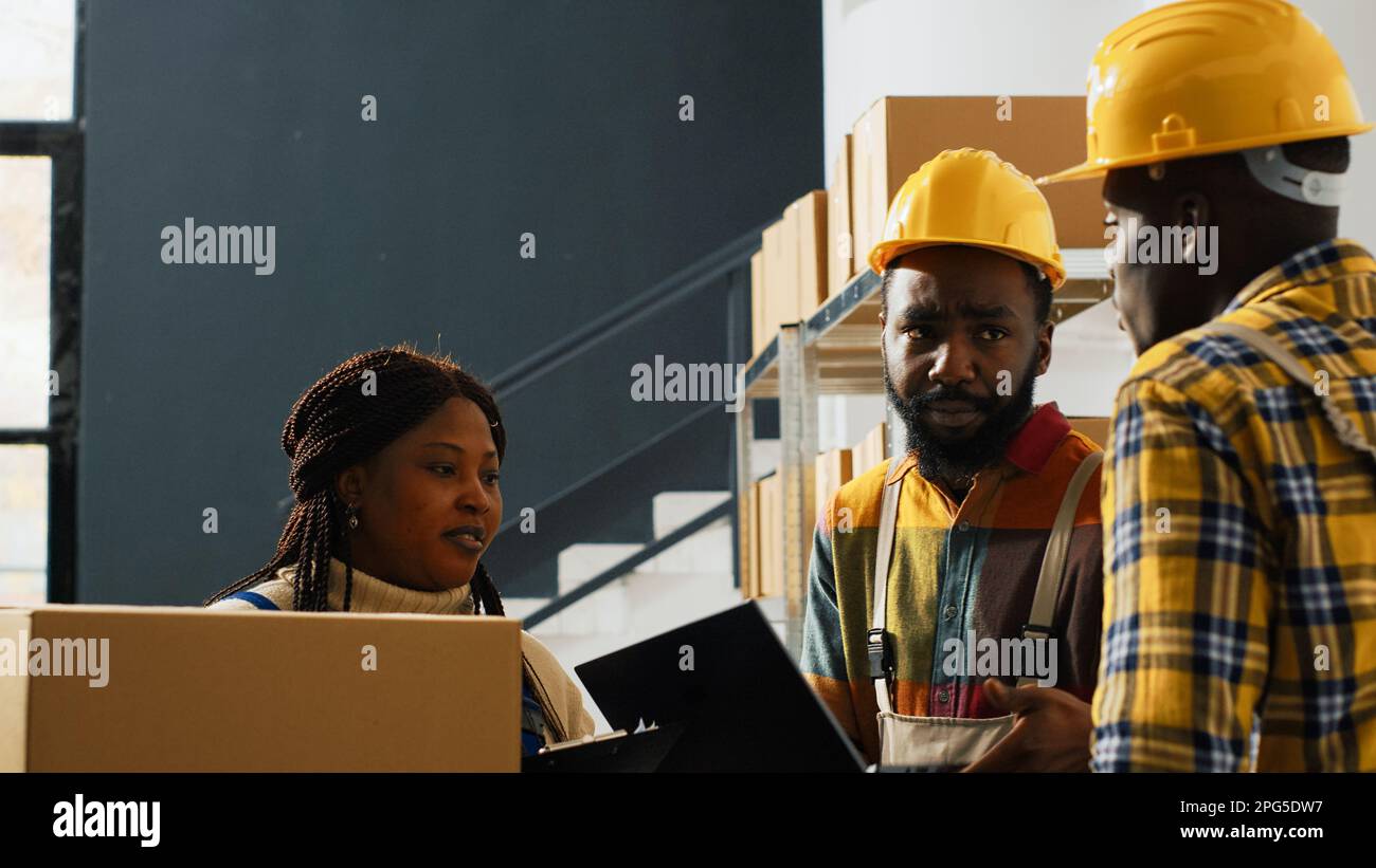 Male workers planning shipment with laptop in depot space, checking ...