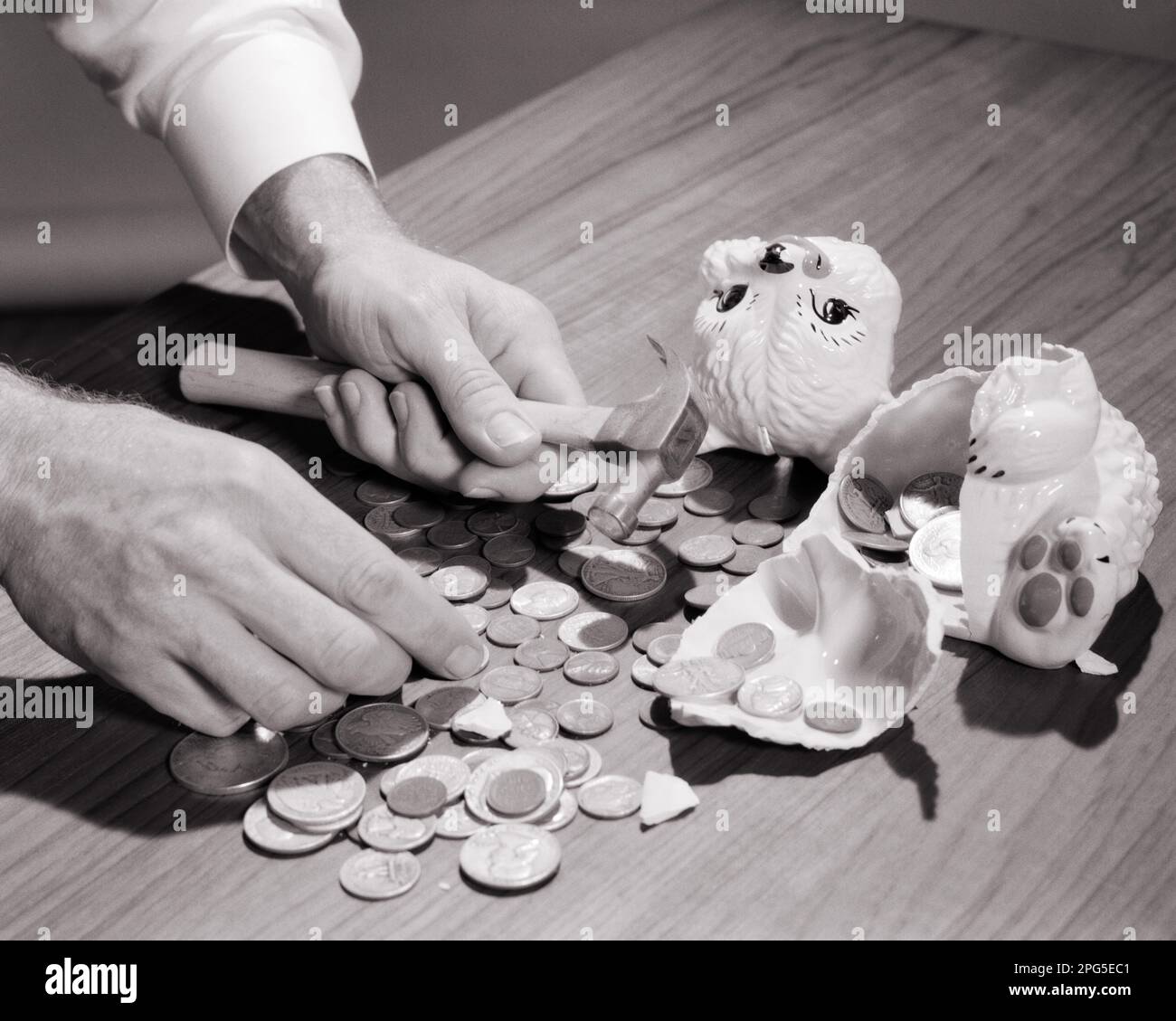 1960s HANDS OF A MAN HOLDING HAMMER PICKING UP COINS FROM BROKEN OPEN ...