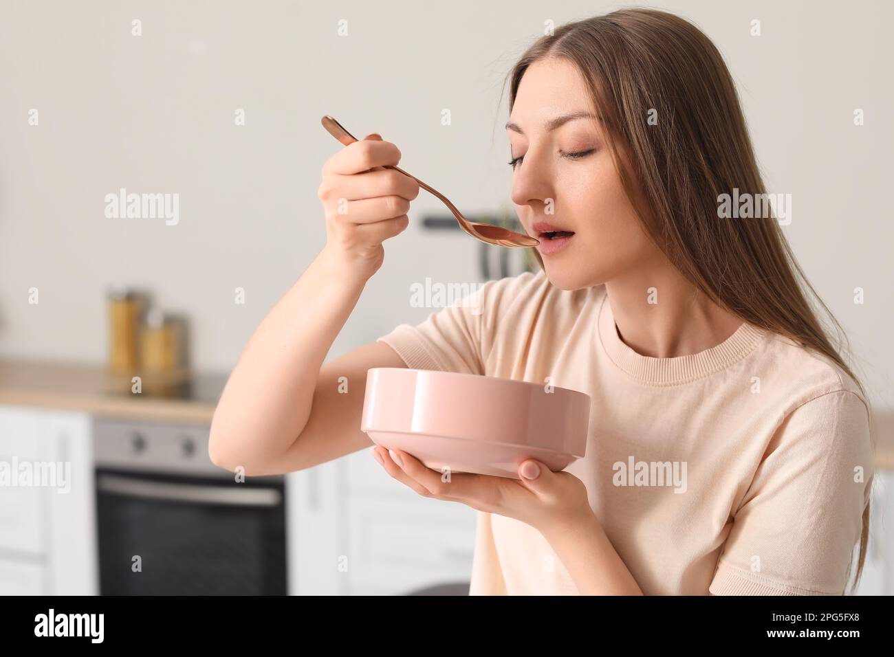 Beautiful woman eating with spoon in kitchen Stock Photo - Alamy