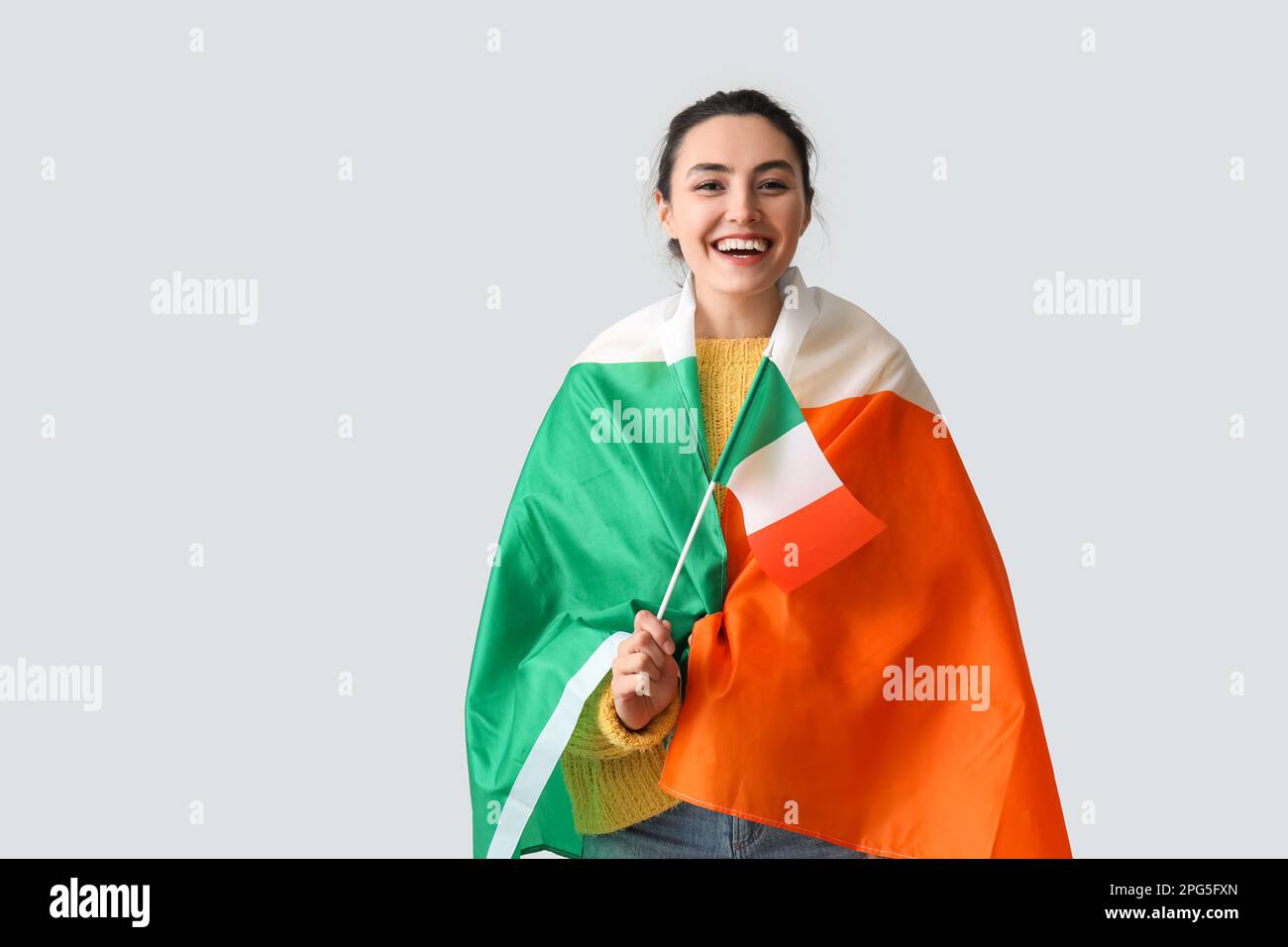 Young woman with flags of Ireland on grey background Stock Photo - Alamy