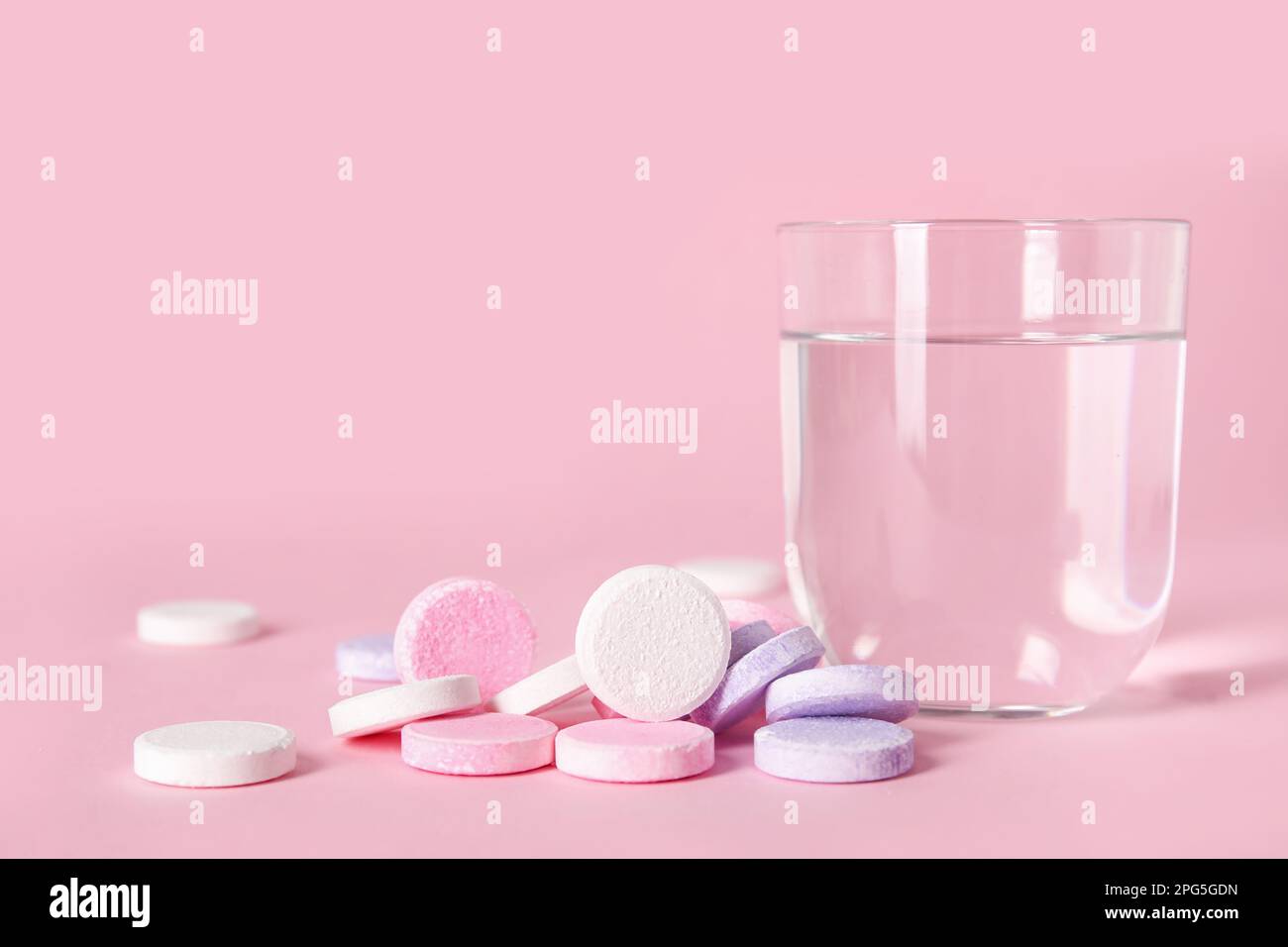 Soluble tablets and glass of water on pink background Stock Photo - Alamy