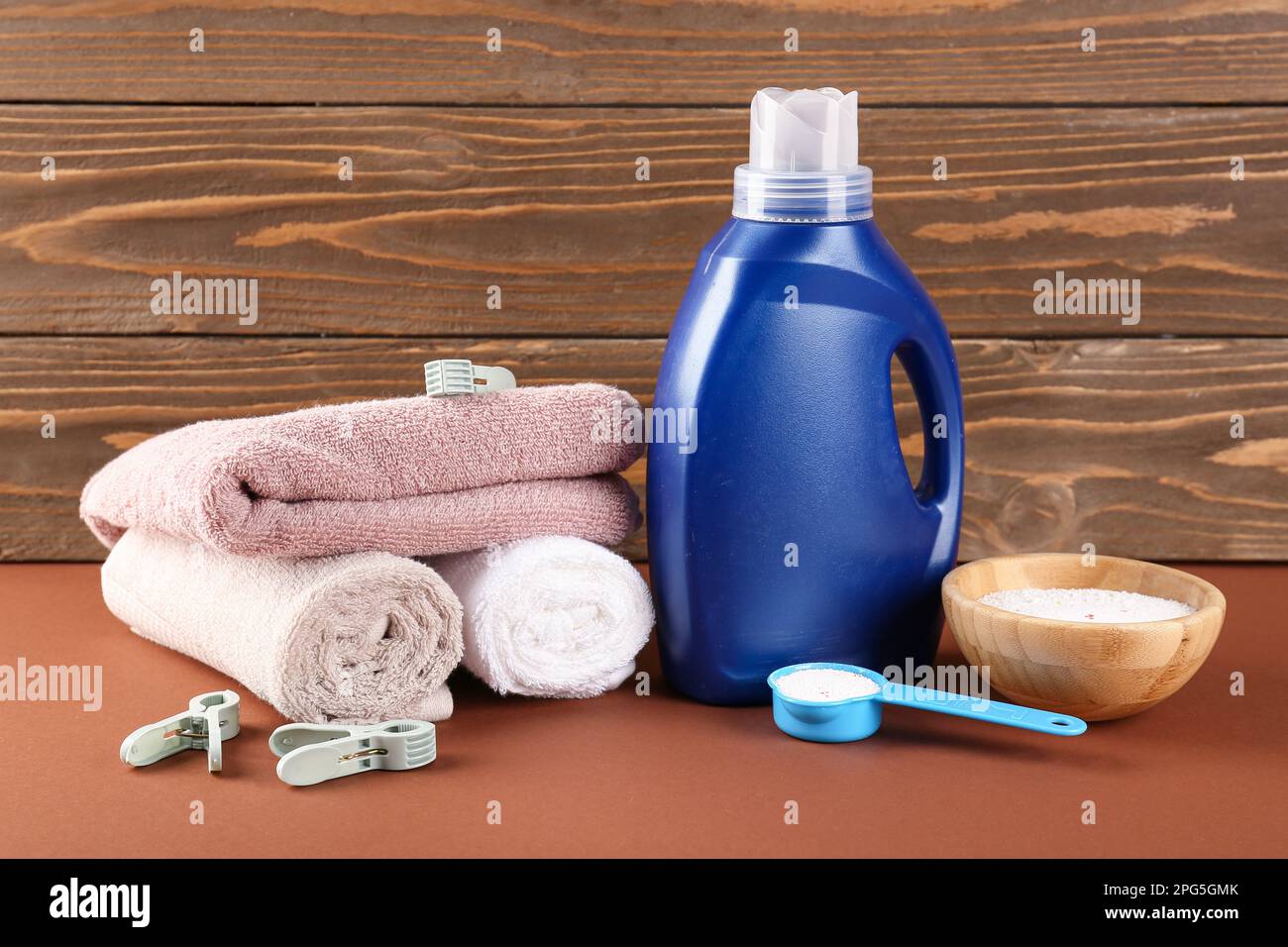 Laundry detergents, clothespins and towels on brown table against ...