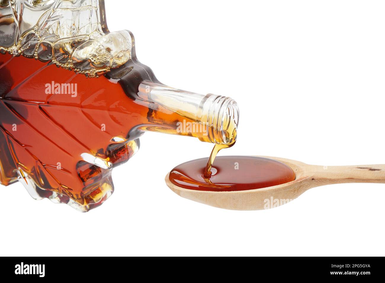 Pouring of tasty maple syrup from bottle into spoon on white background ...