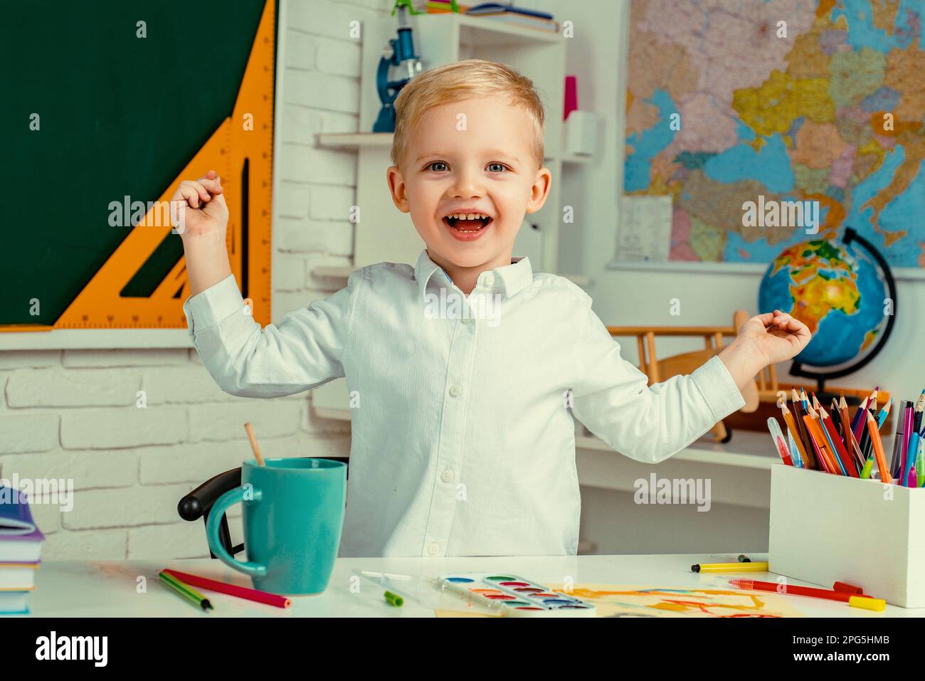 Happy child boy in classroom near blackboard desk. Funny school kids at ...
