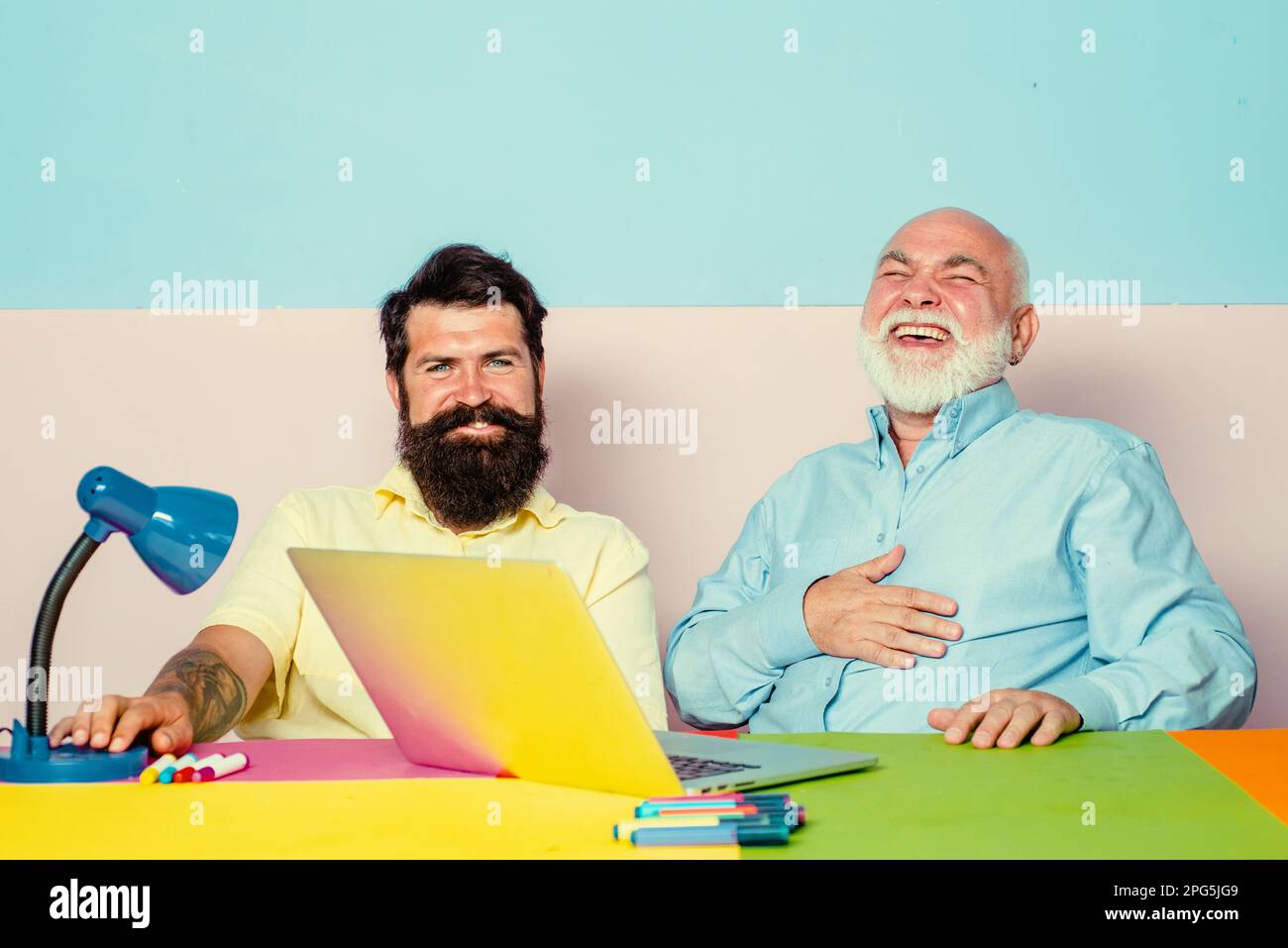 Couple of two young office workers laugh looking at laptop screen ...