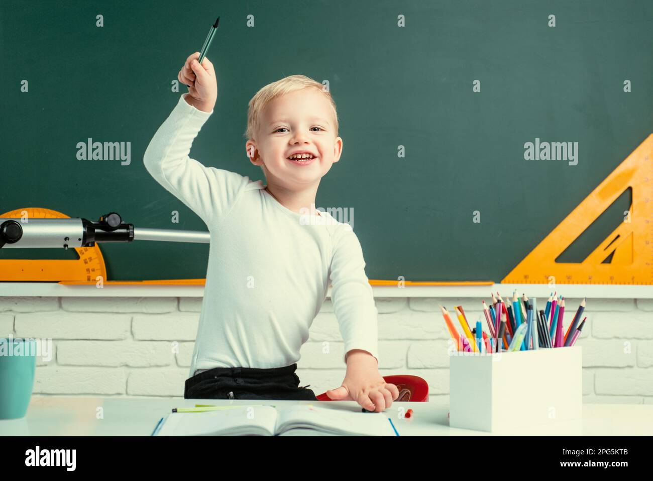 Friendly child in classroom near blackboard desk. Talented child. Kid ...