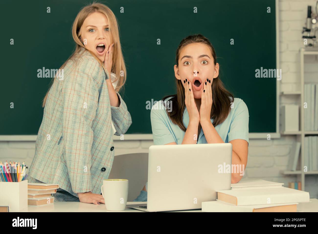 Two surprised students girls friends in classroom at school college or ...