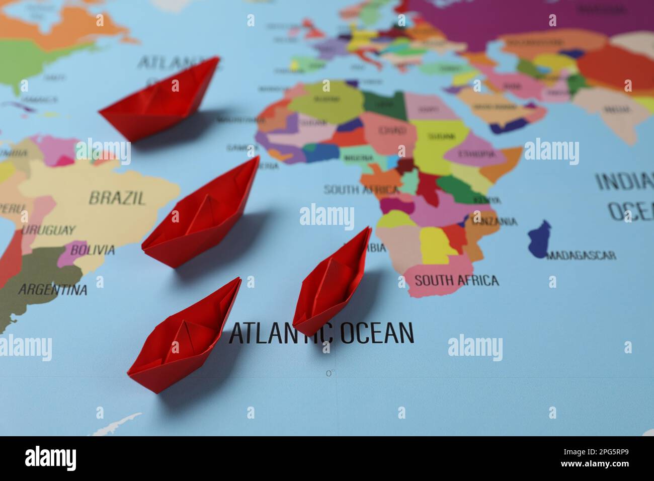 Red paper boats on world map. Space for text Stock Photo - Alamy