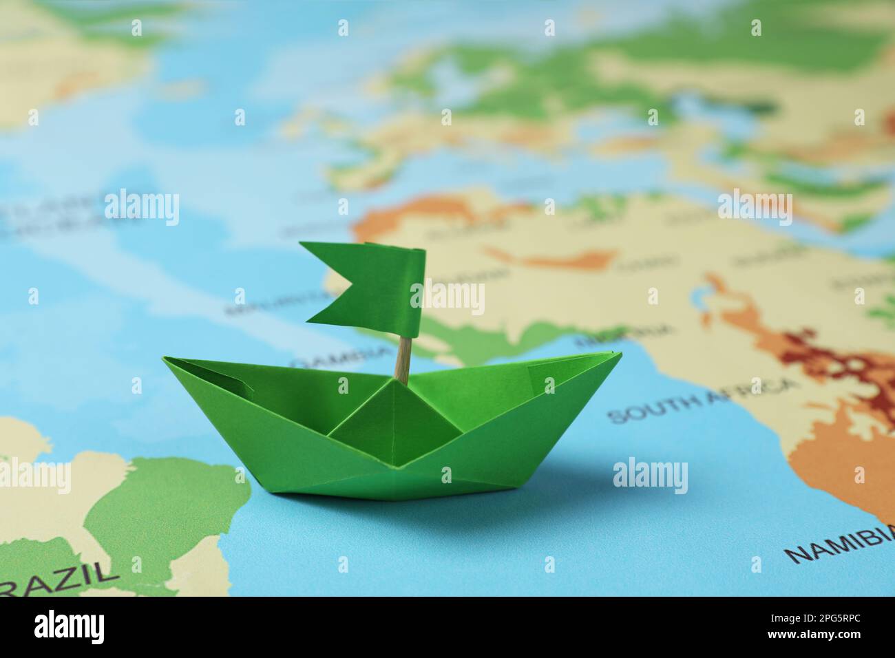 Green paper boat with flag on world map Stock Photo - Alamy