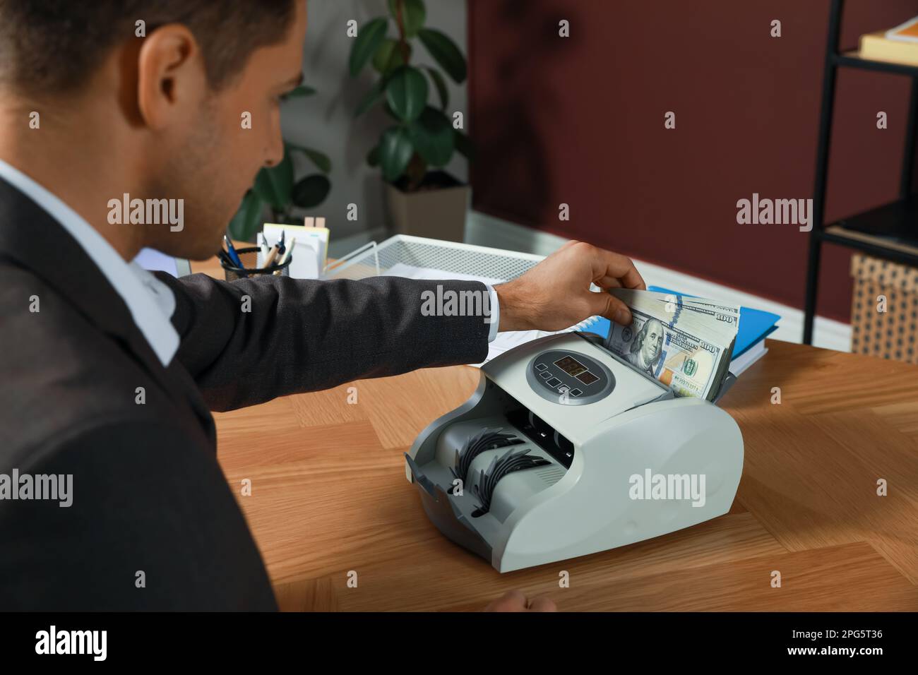 Man putting money into banknote counter at wooden table indoors Stock ...