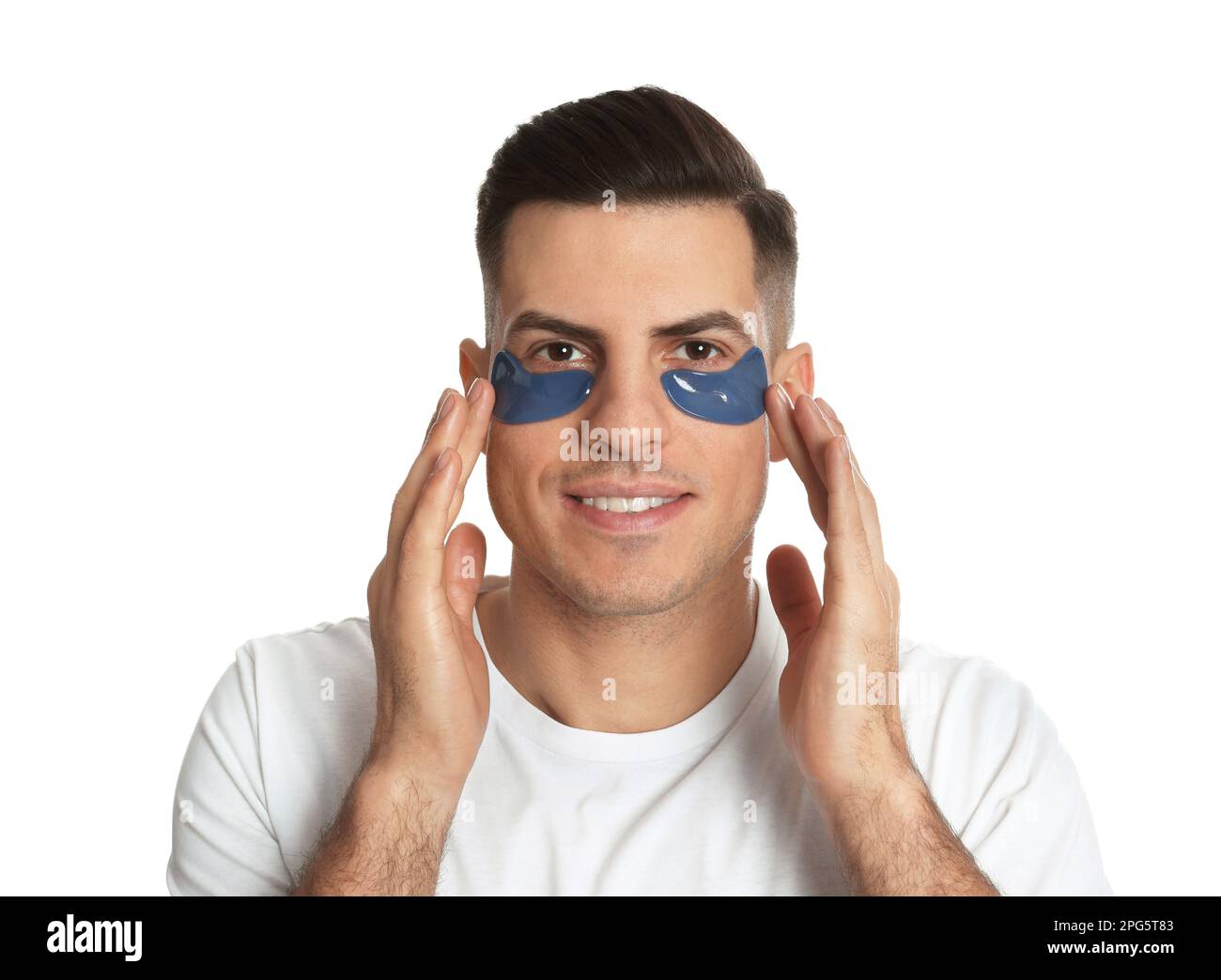 Man applying blue under eye patches on white background Stock Photo - Alamy
