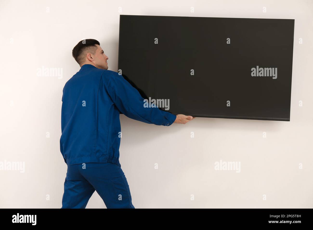 Professional technician installing modern flat screen TV on wall ...