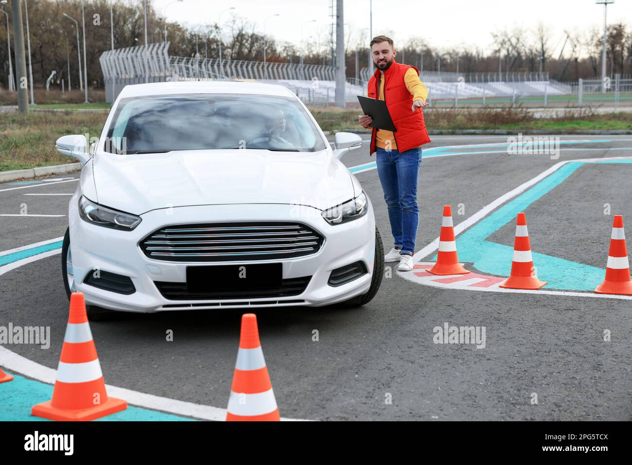 Instructor near car with his student during exam at driving school test ...