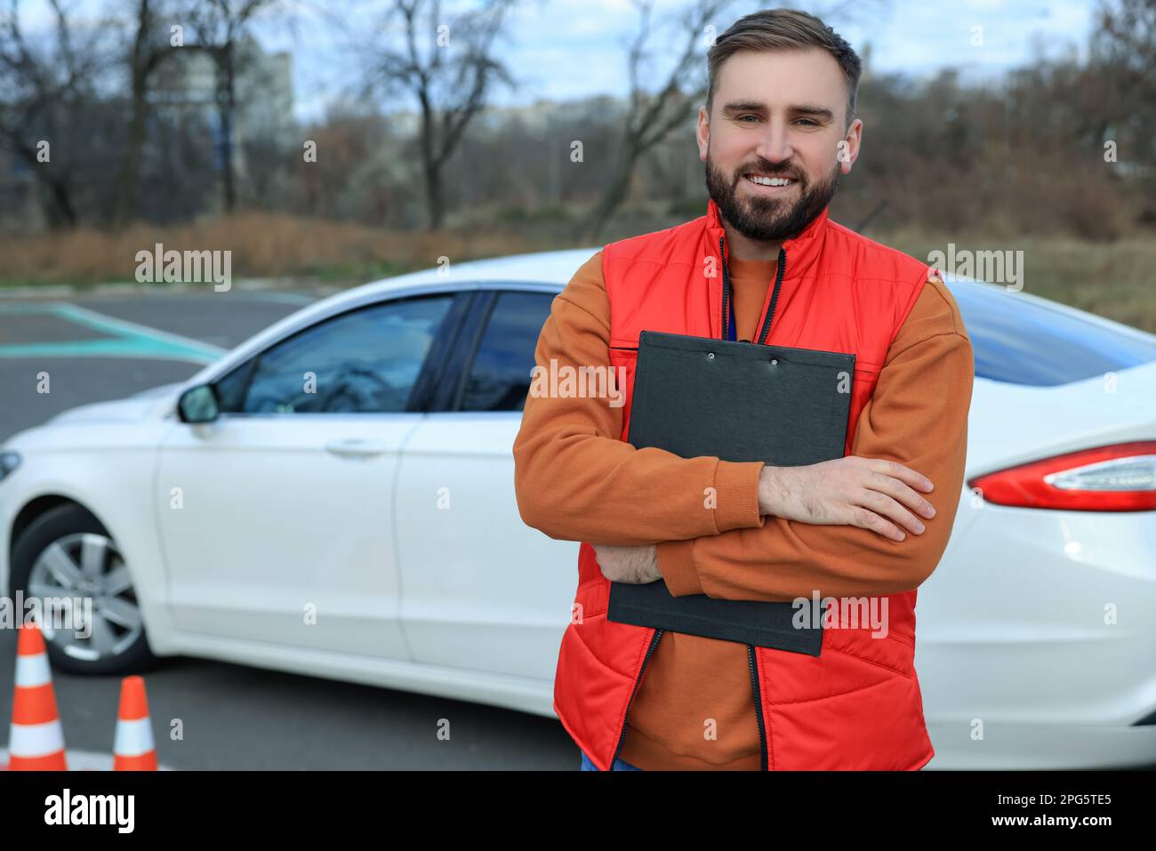 Instructor with clipboard near car on test track. Driving school Stock ...