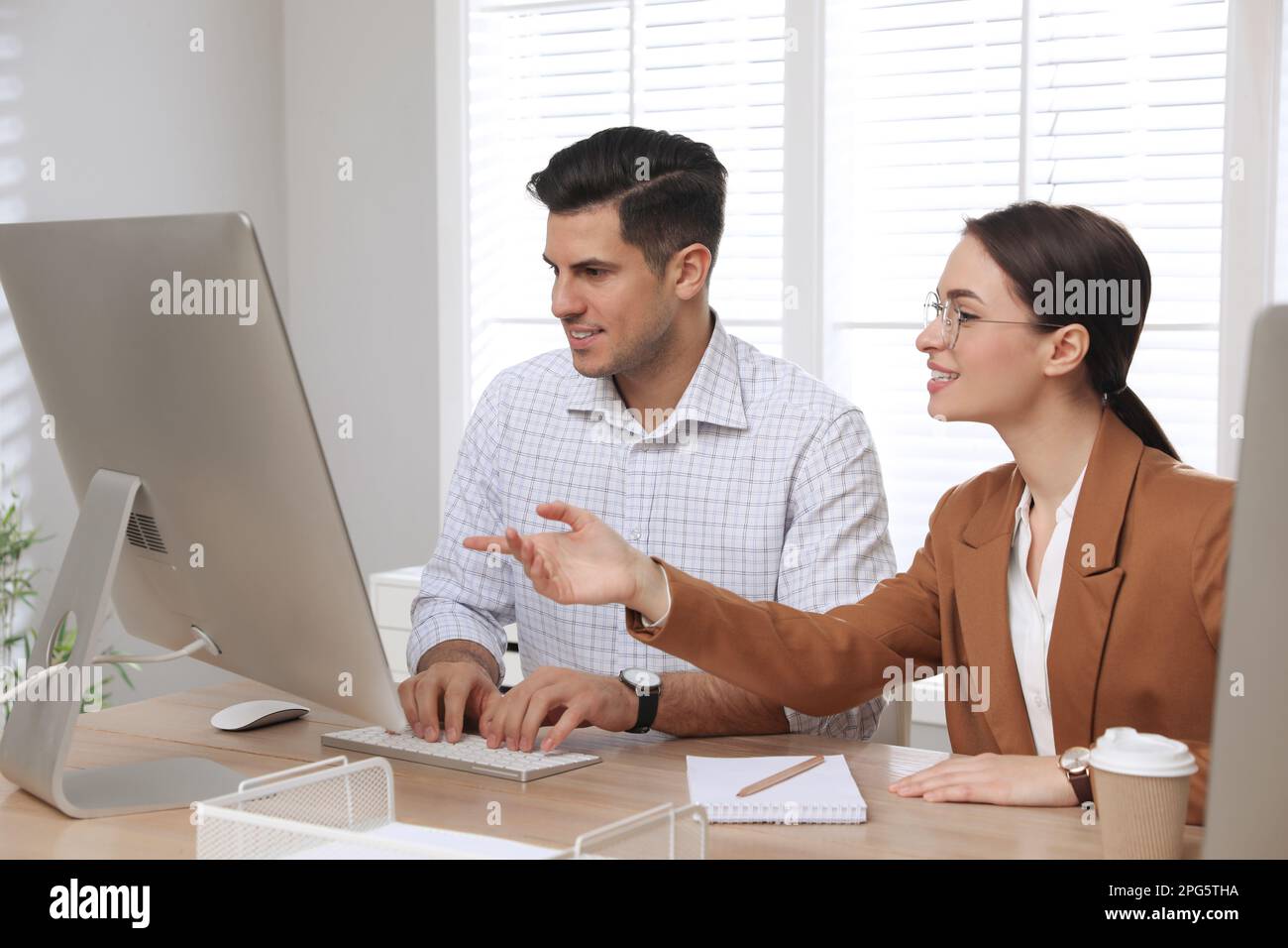 Businesswoman helping intern with work in office Stock Photo - Alamy