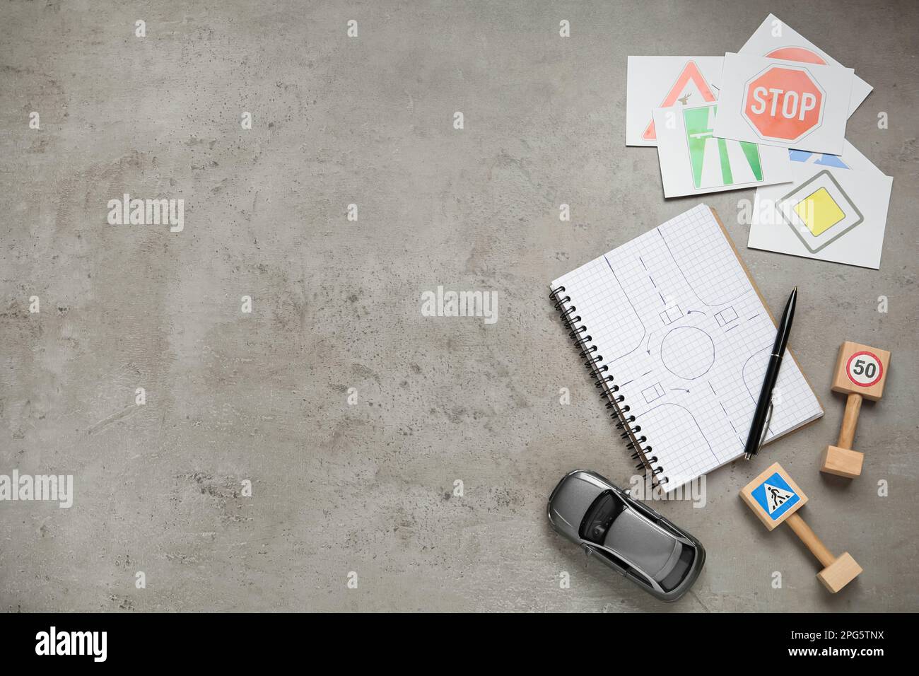 Many different road signs, notebook and toy car on grey background ...