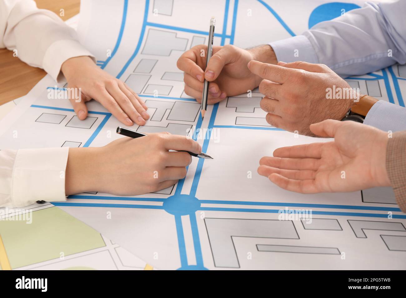 Professional cartographers working with cadastral map at table, closeup ...
