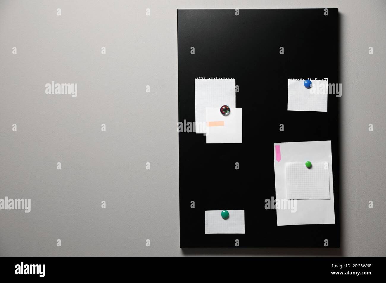 Many notes attached to magnetic black board on grey wall, space for ...