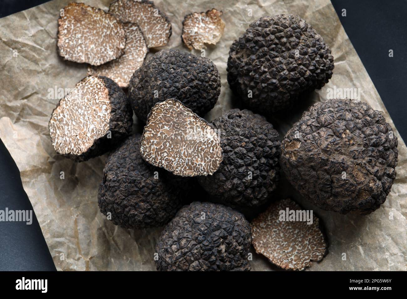 Whole and cut black truffles on parchment, top view Stock Photo - Alamy