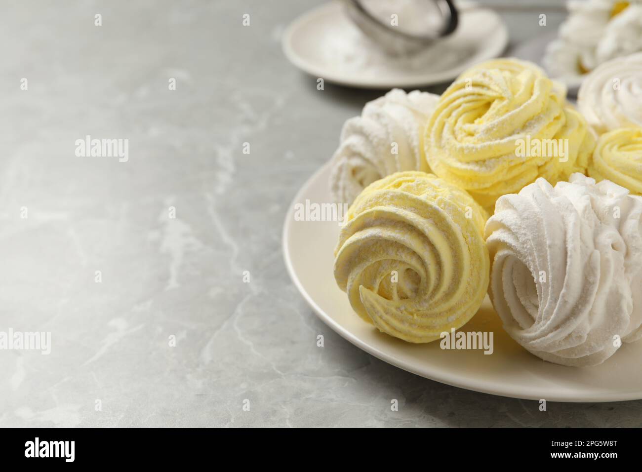 Delicious white and yellow marshmallows on grey marble table. Space for ...