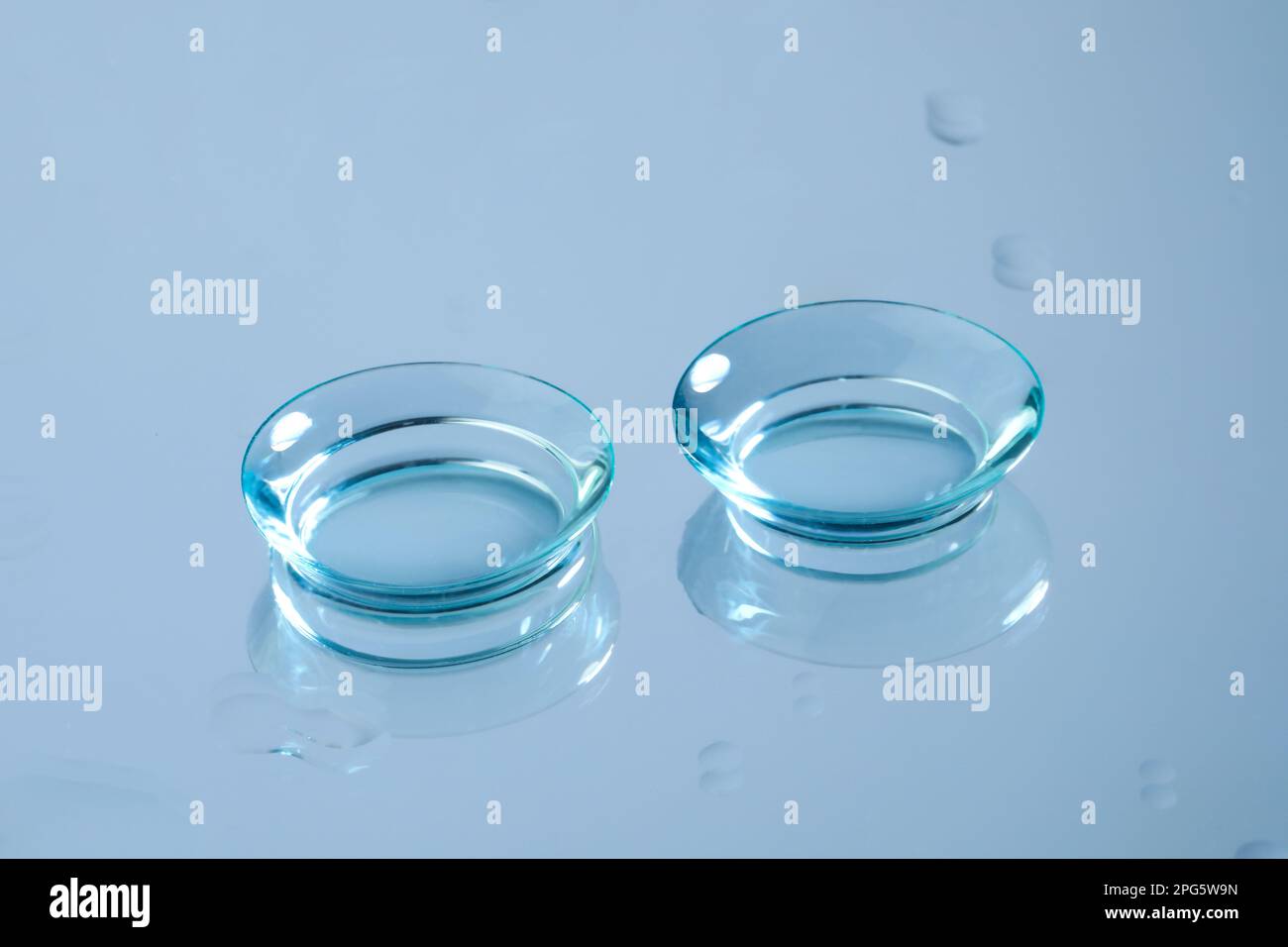 Pair of contact lenses on wet light blue reflective surface Stock Photo ...