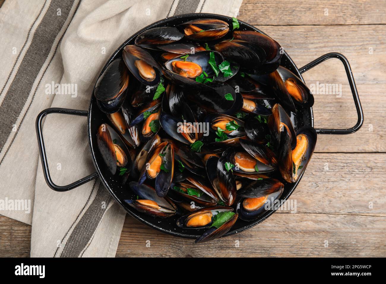 Pan of cooked mussels with parsley on wooden table, top view Stock ...