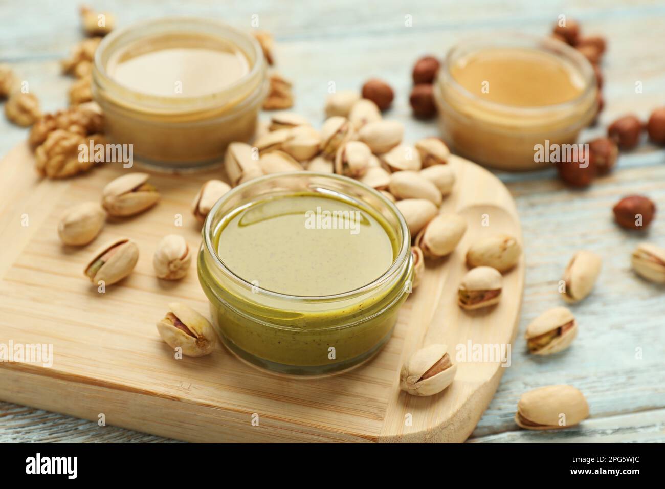 Different types of delicious nut butters and ingredients on light blue ...