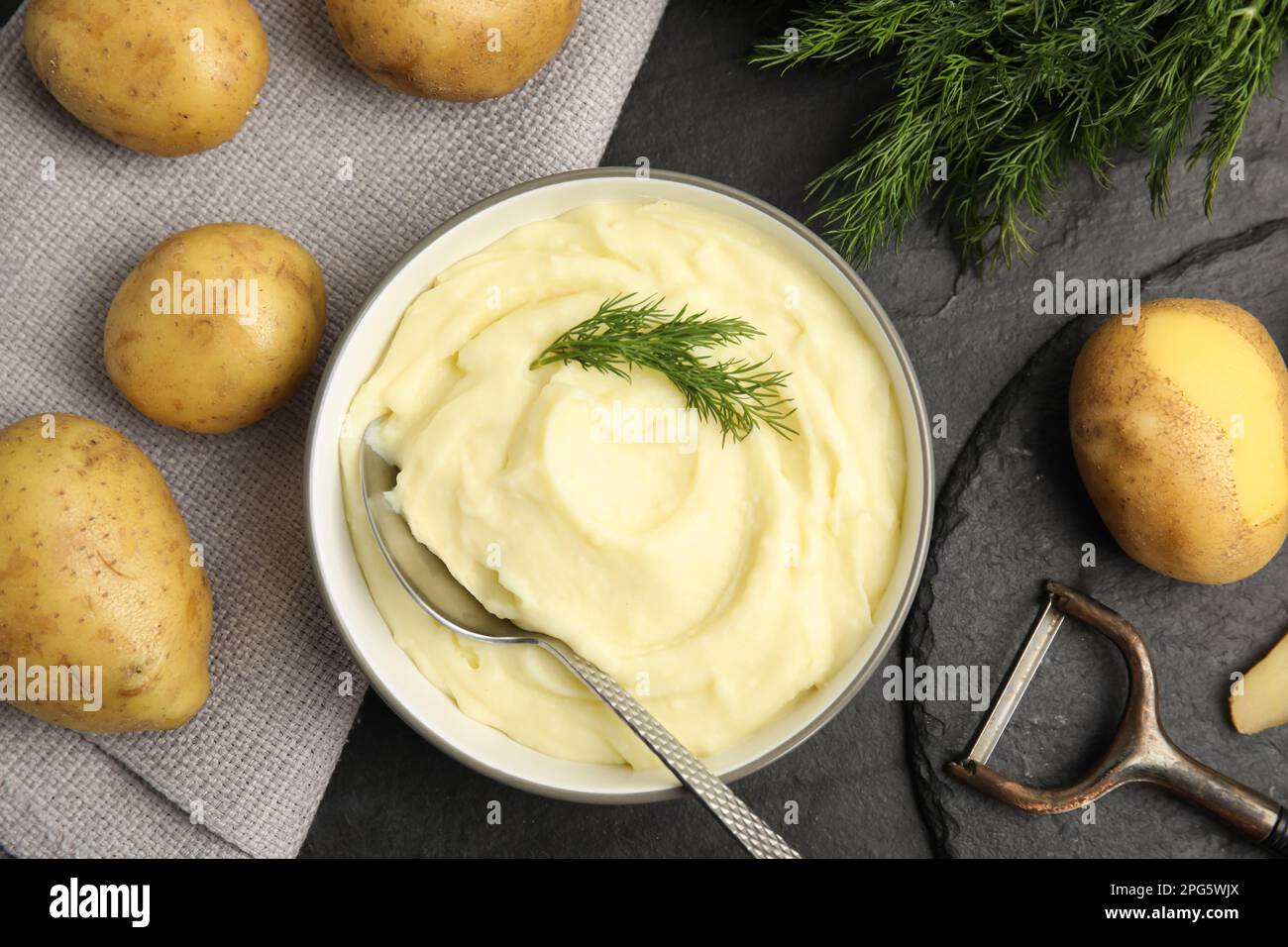 Freshly cooked homemade mashed potatoes and raw ingredients on black ...