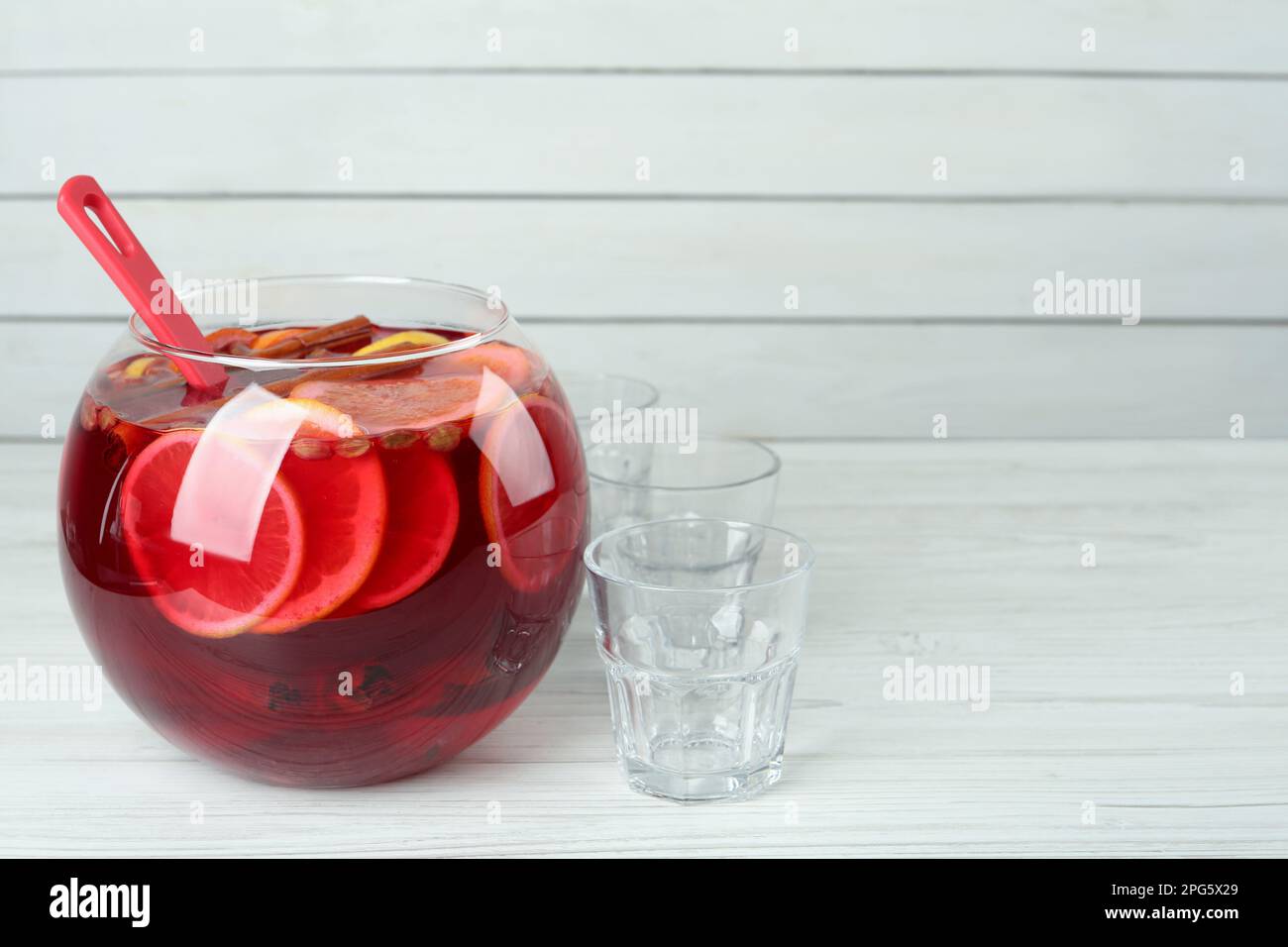 Empty glasses and ladle near bowl of aromatic punch drink on white ...