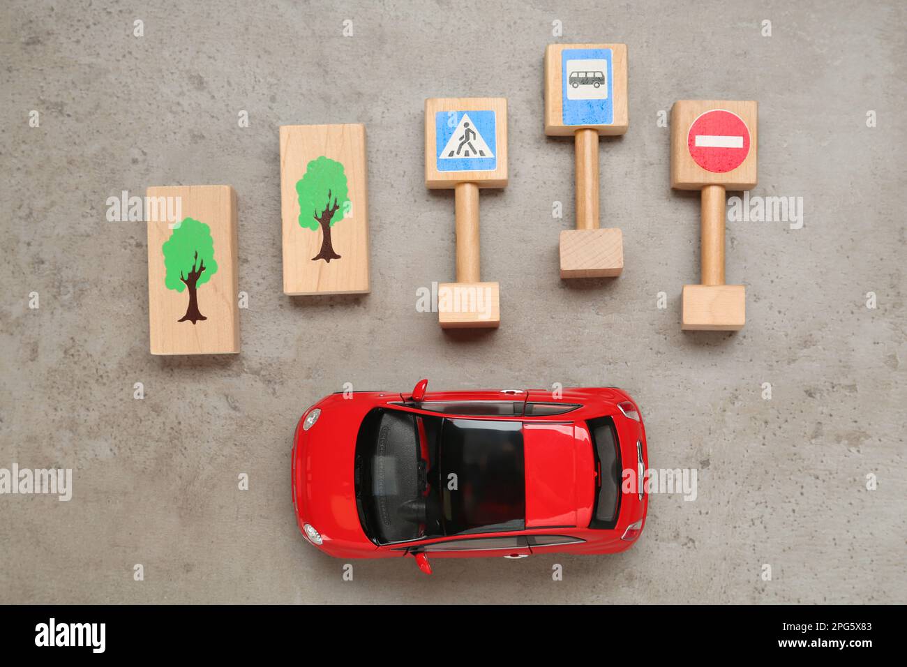 Miniature road signs, trees and car on grey table, flat lay. Driving ...