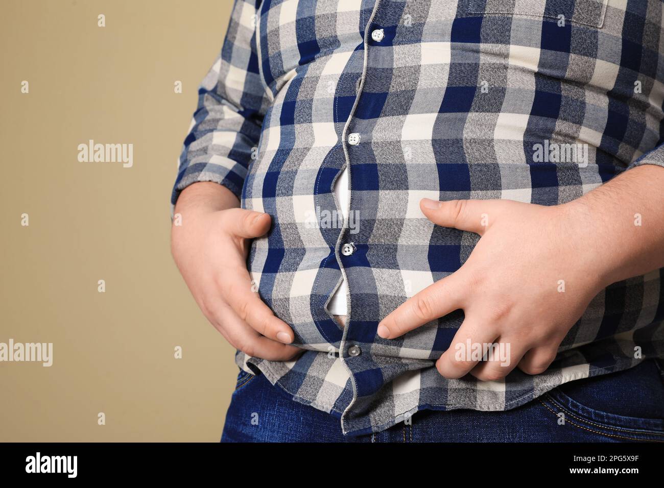 Overweight man in tight shirt on beige background, closeup Stock Photo ...