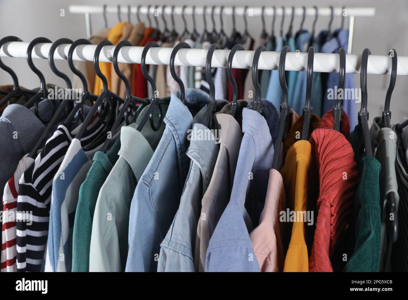 Rack with stylish clothes on blurred background, closeup. Fast fashion ...