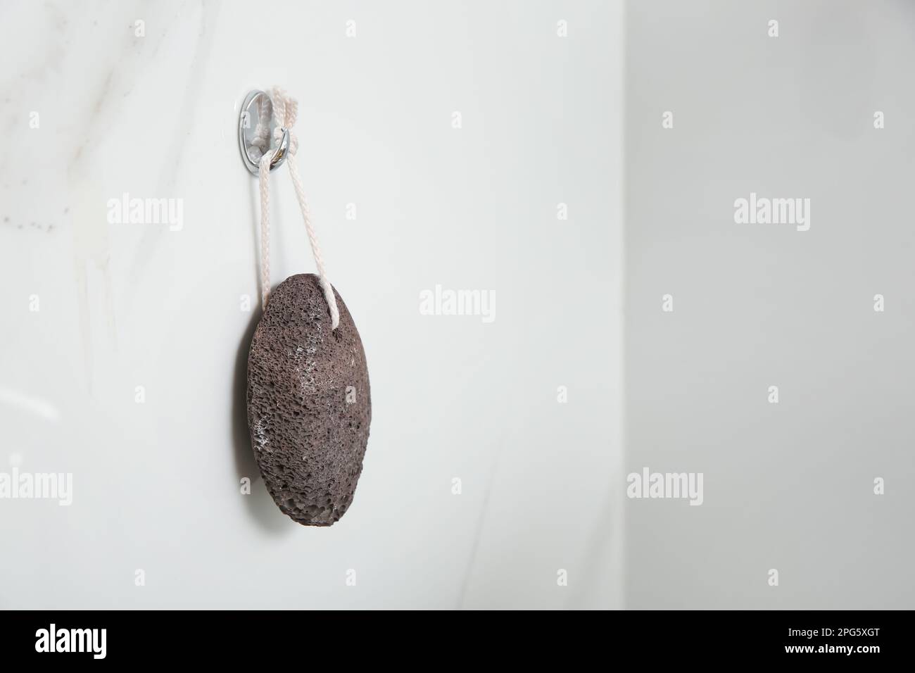 Pumice stone hanging on white wall, space for text Stock Photo - Alamy