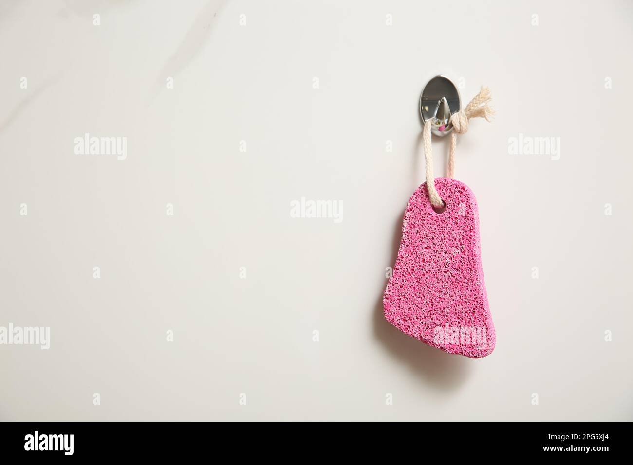 Pink pumice stone hanging on white wall, space for text Stock Photo - Alamy